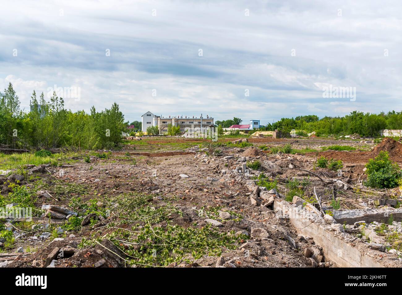 Cleared construction site with broken concrete on ground. In background ...
