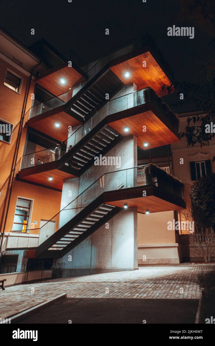 A low angle shot of a modern fire escape illuminated during the night ...