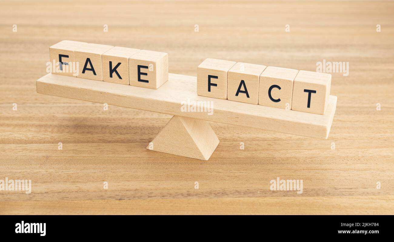 Fake fact words on wooden block on a wood seesaw Stock Photo - Alamy