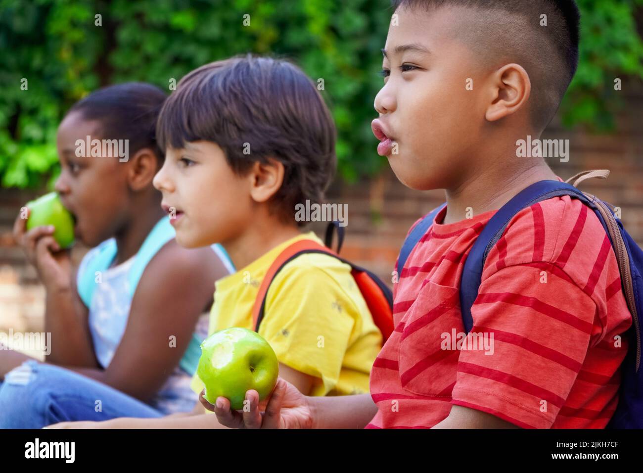 multiethnic kids with backpacks sitting on the street at school ...
