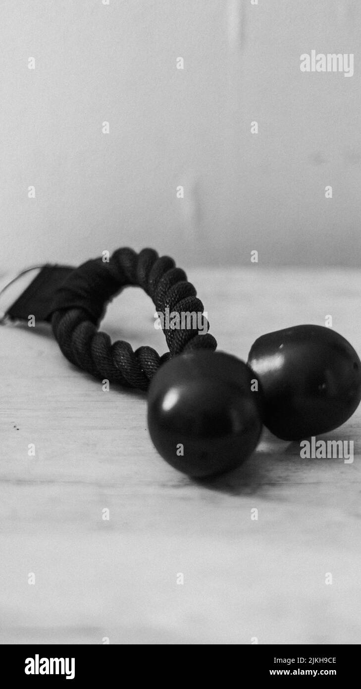 A vertical closeup of black fitness gears, tricep rope on a white ...