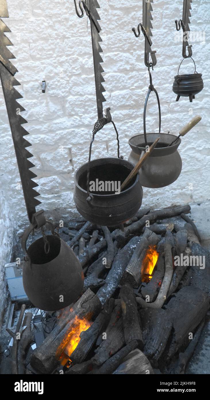 A vertical shot of old and traditional cooking pots hanging over ...