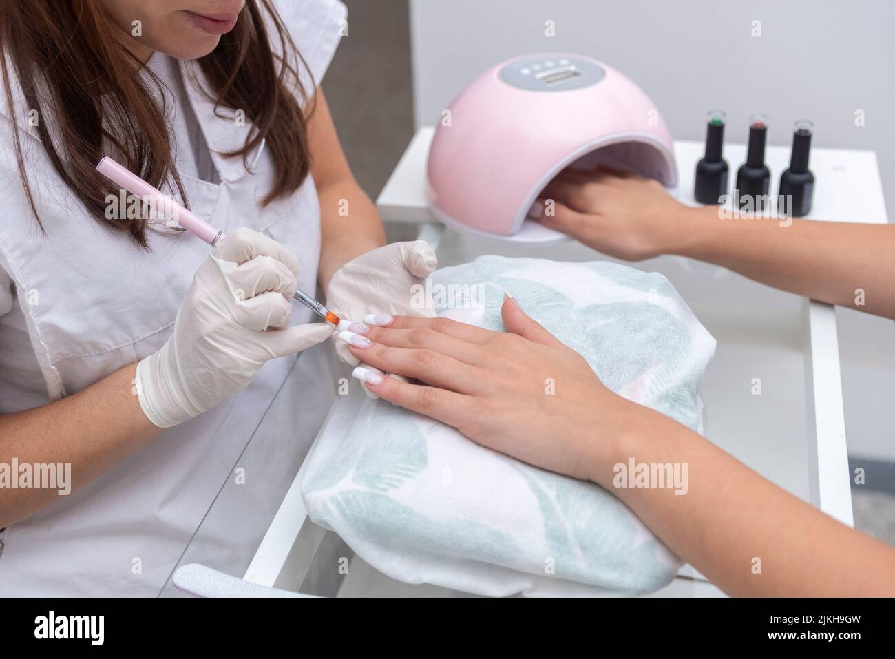 A woman in beauty center performing a nail service and beautification ...