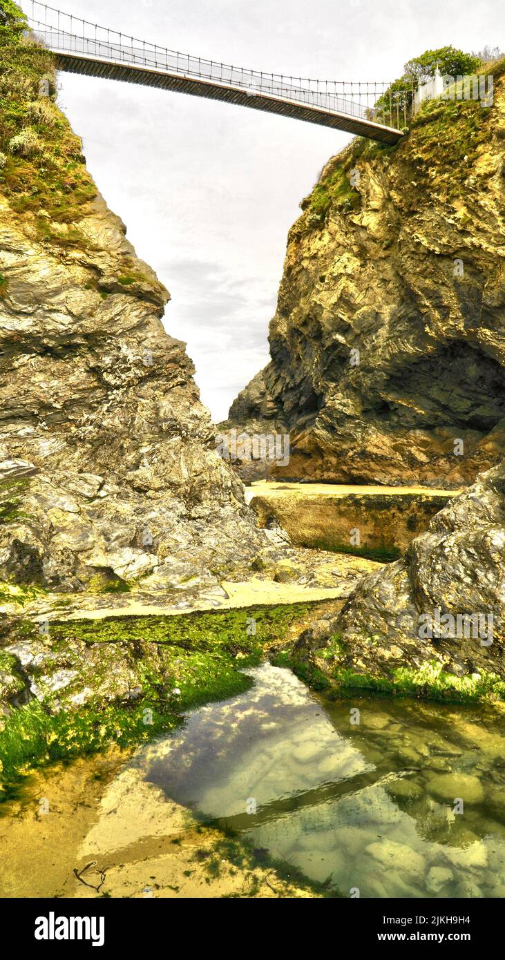 A vertical shot of a hanging footbridge connecting two rock formations ...