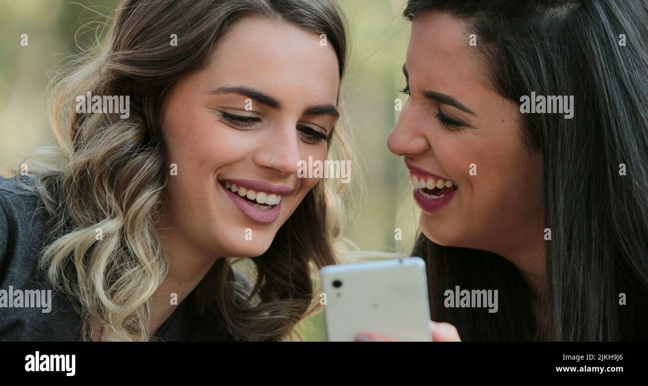 Authentic friends laughing together outdoors checking cellphone Close ...