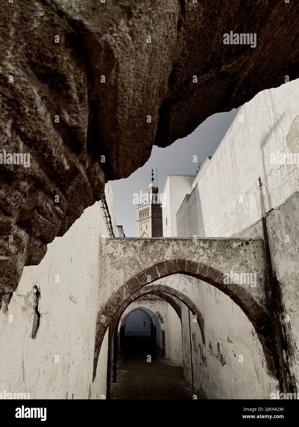 A vertical shot of narrow tunnel-like alley between white buildings ...
