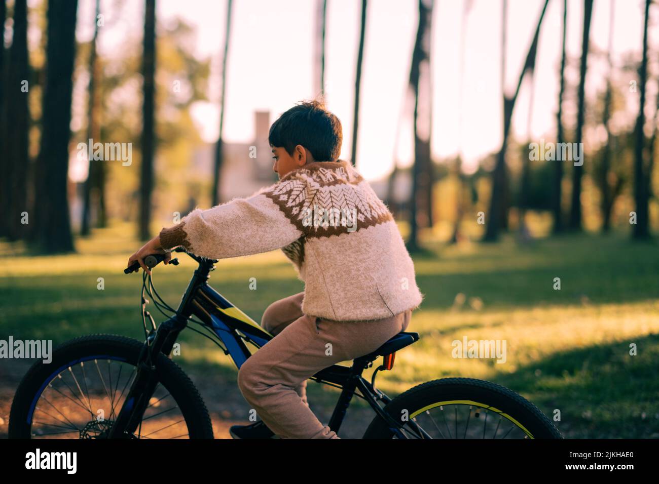 A young boy in a sweater riding a bike Stock Photo - Alamy