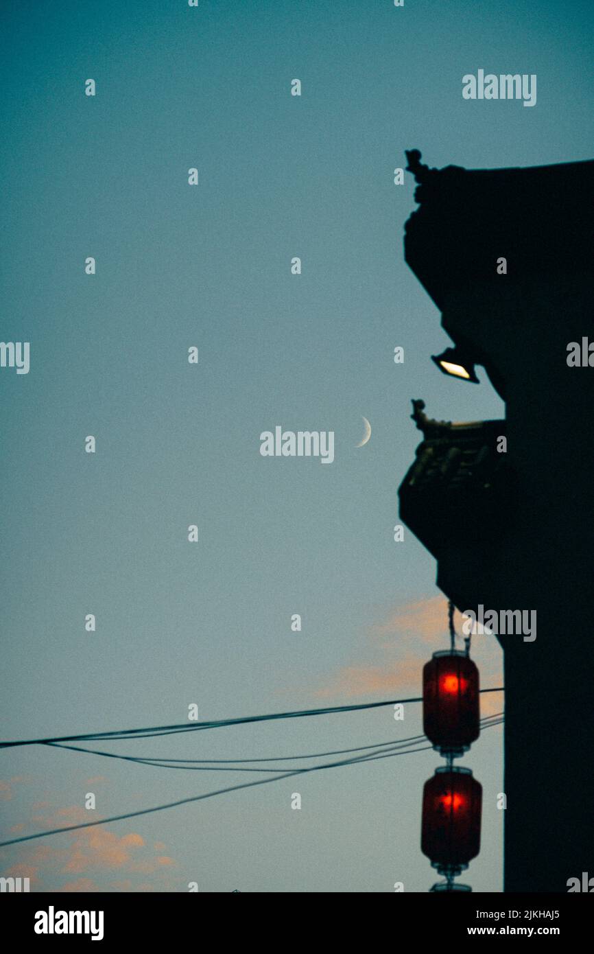 A beautiful view of a crescent moon in a blue sky and traffic lights in ...