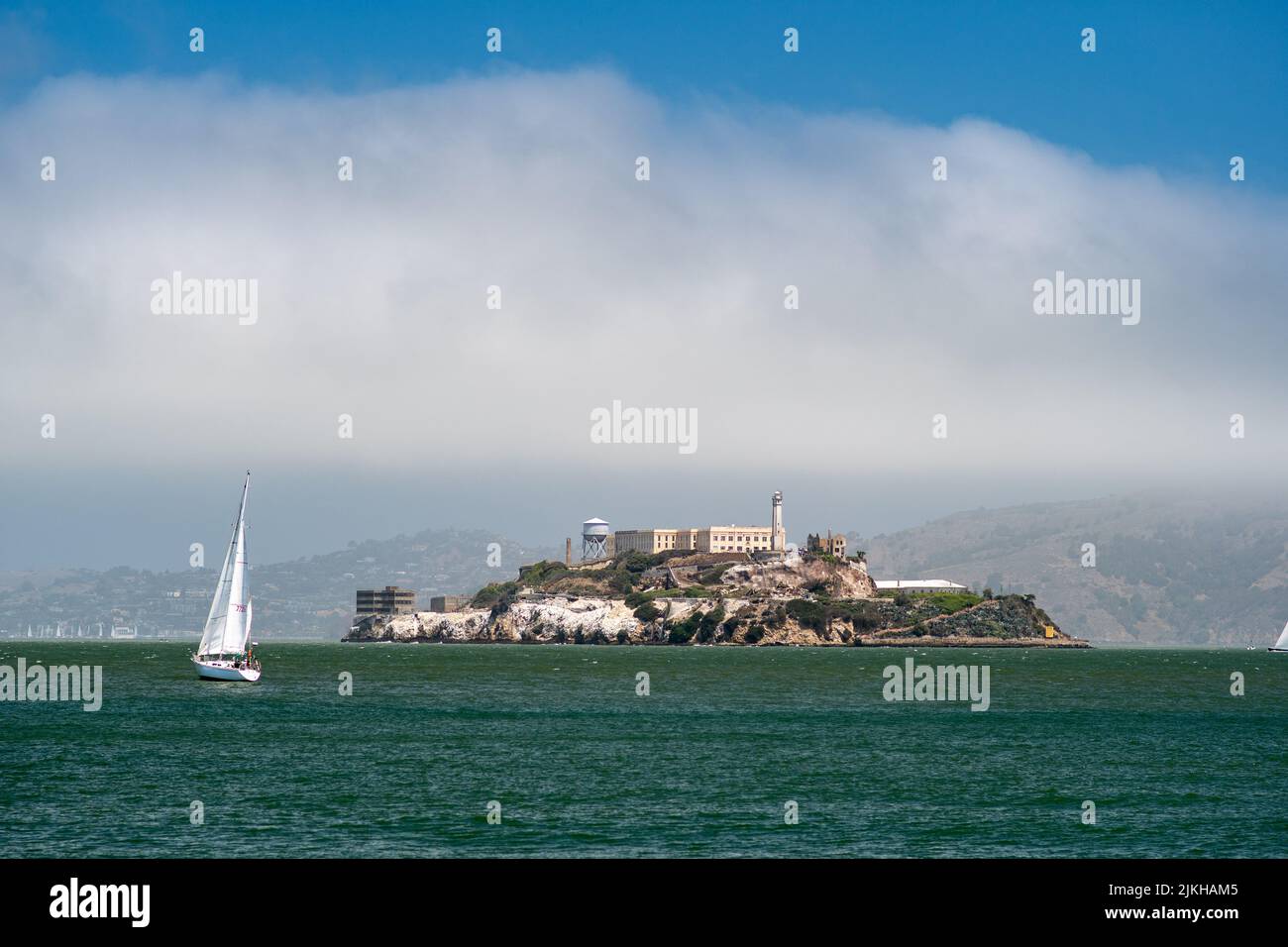 A white sailboat floating near the historic Alcatraz Prison Stock Photo ...