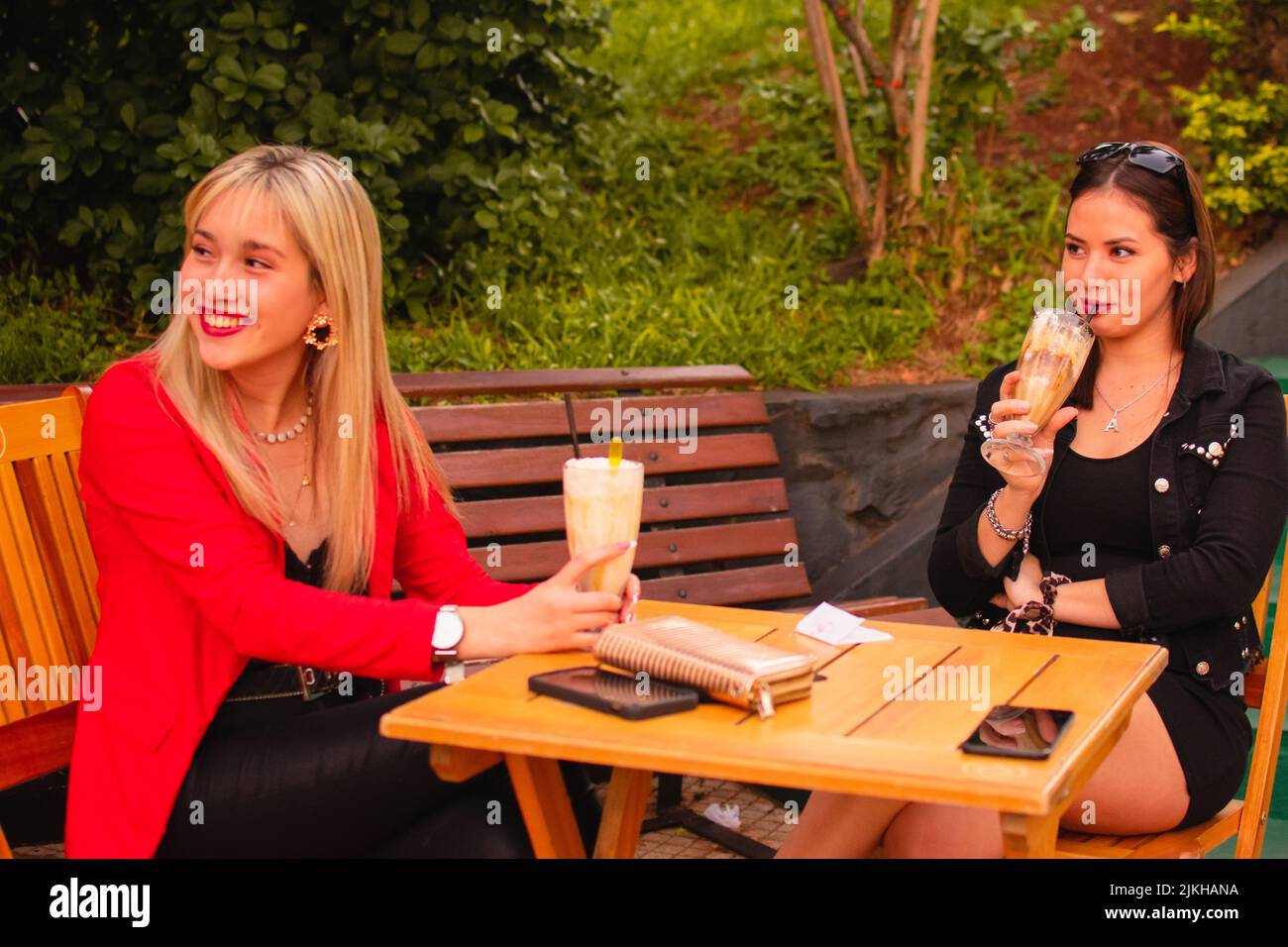 Beautiful friends taking a break in a cafe and drinking a milk cocktail ...