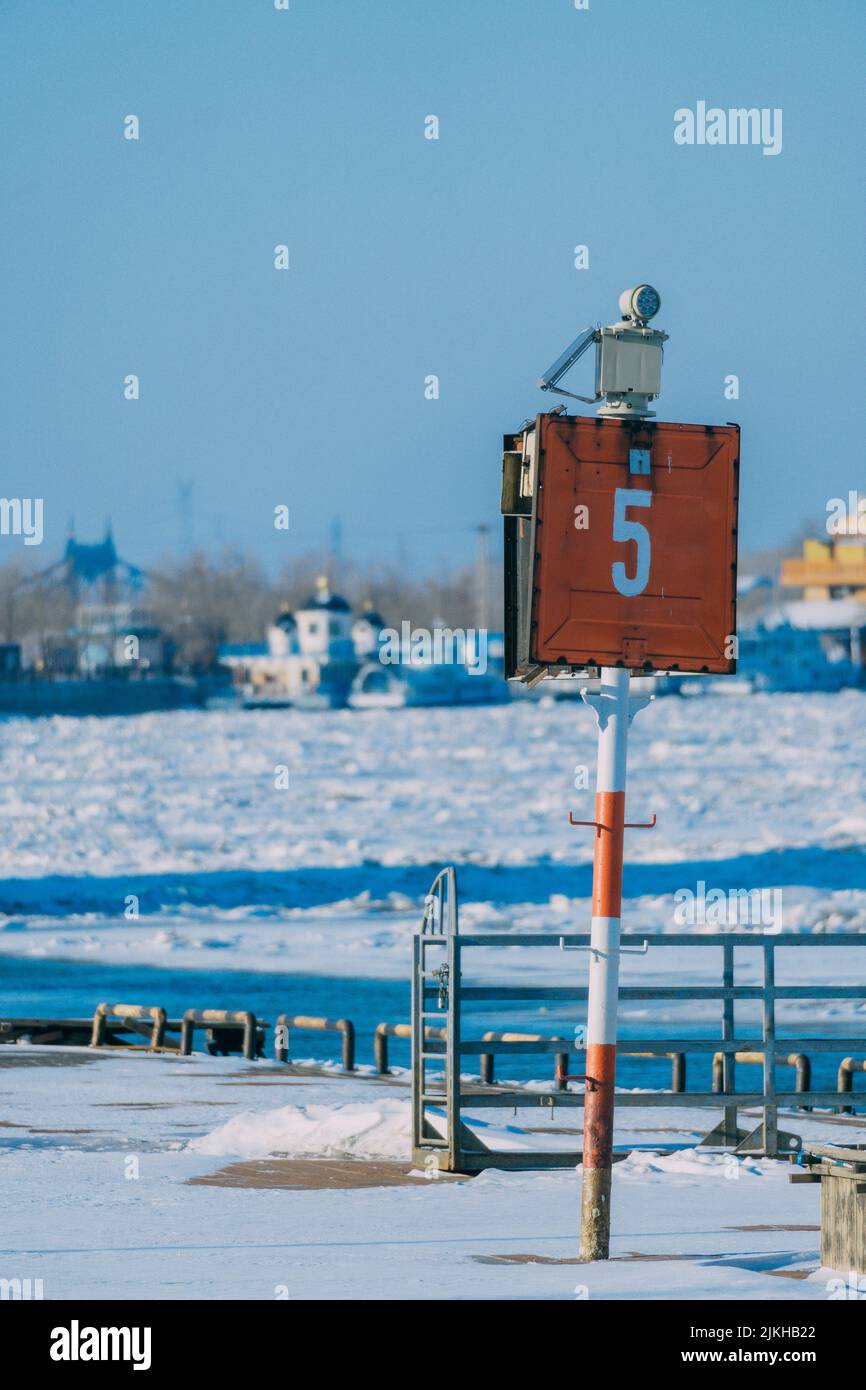 A vertical shot of a metal pole with wooden stand number 5 on the beach ...