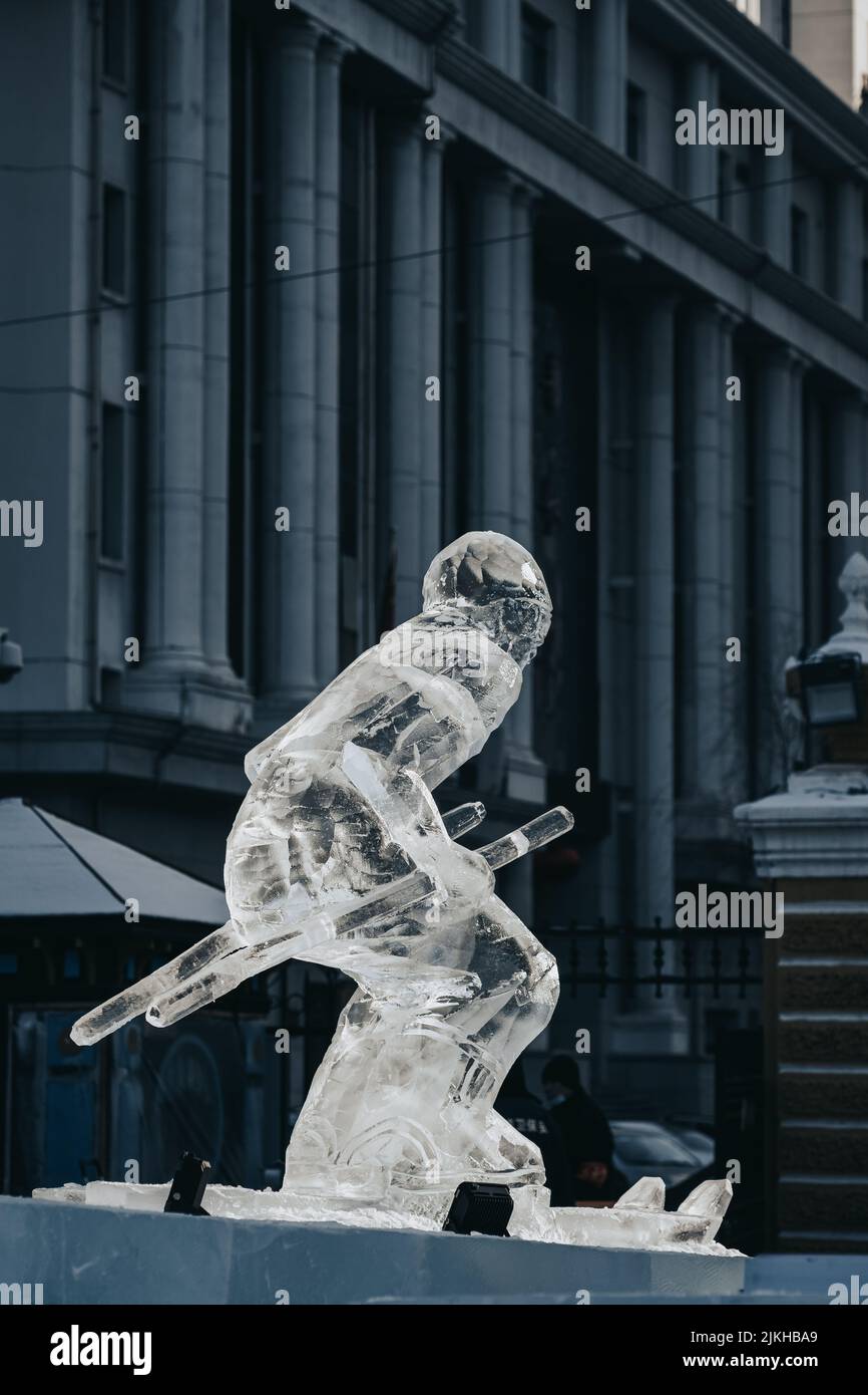 A vertical shot of an ice sculpture of a male with fighting sticks ...