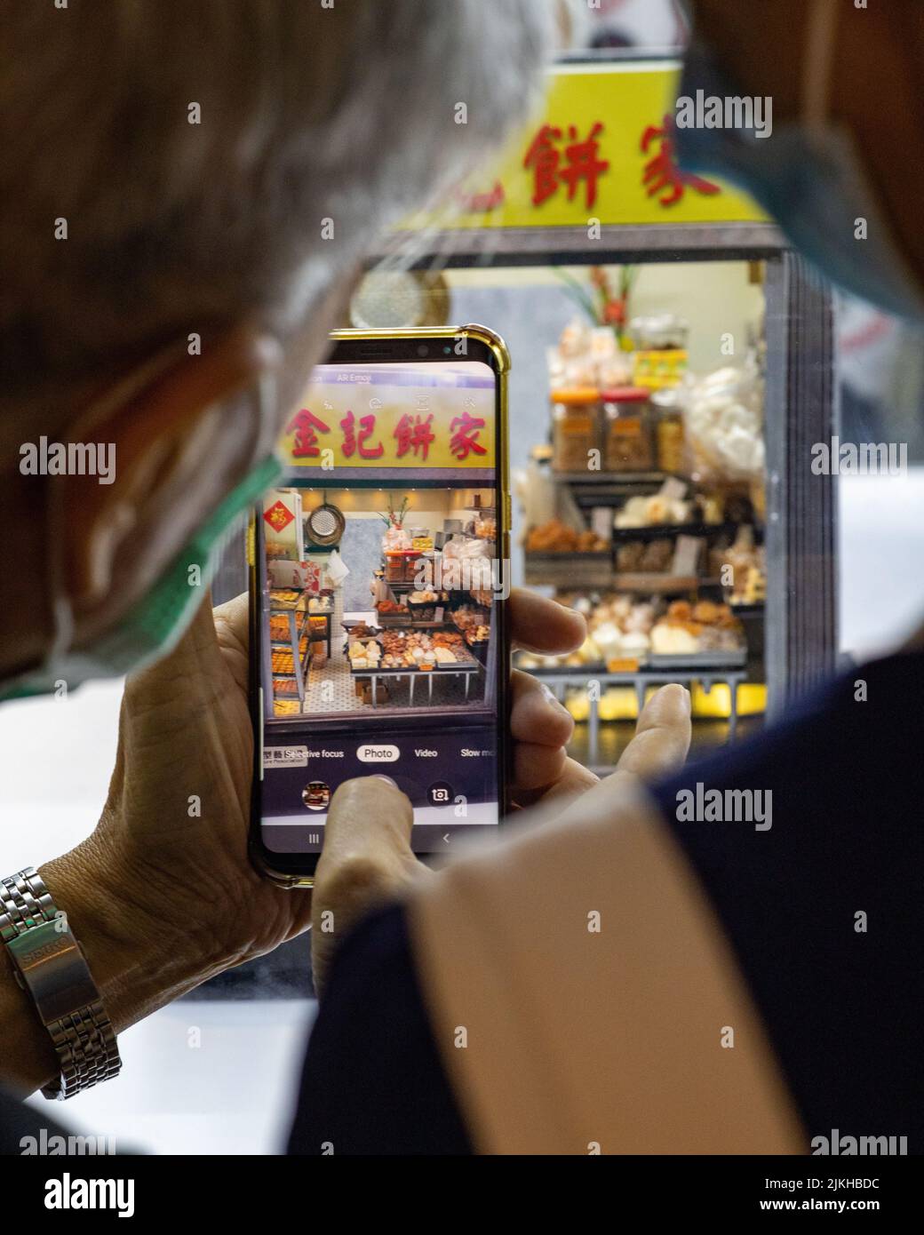 A vertical shot of people taking a photo of a mini pastry shop ...