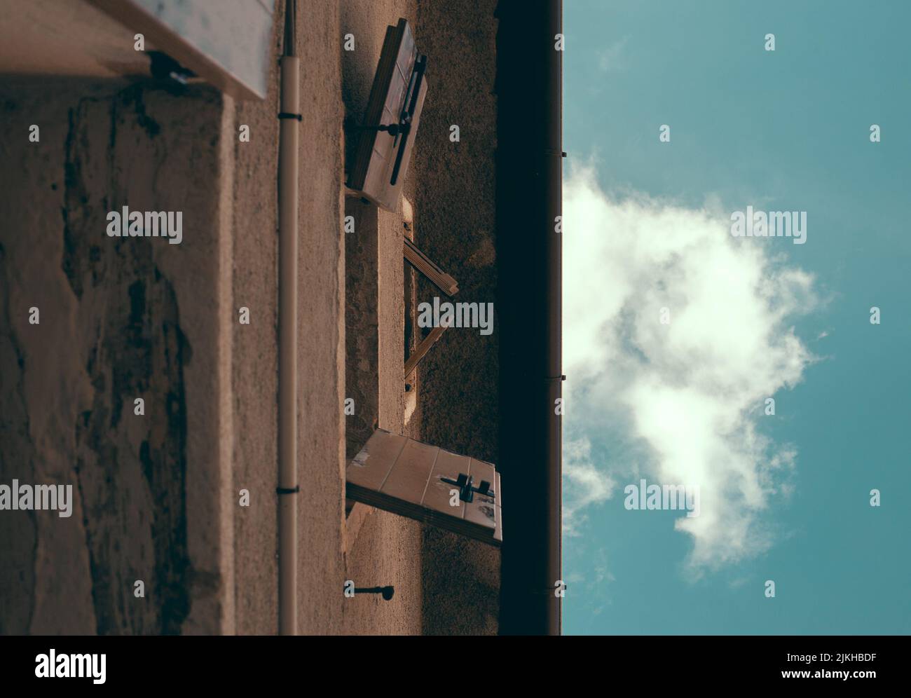 A vertical flipped shot of open wooden windows of a building in cloudy ...