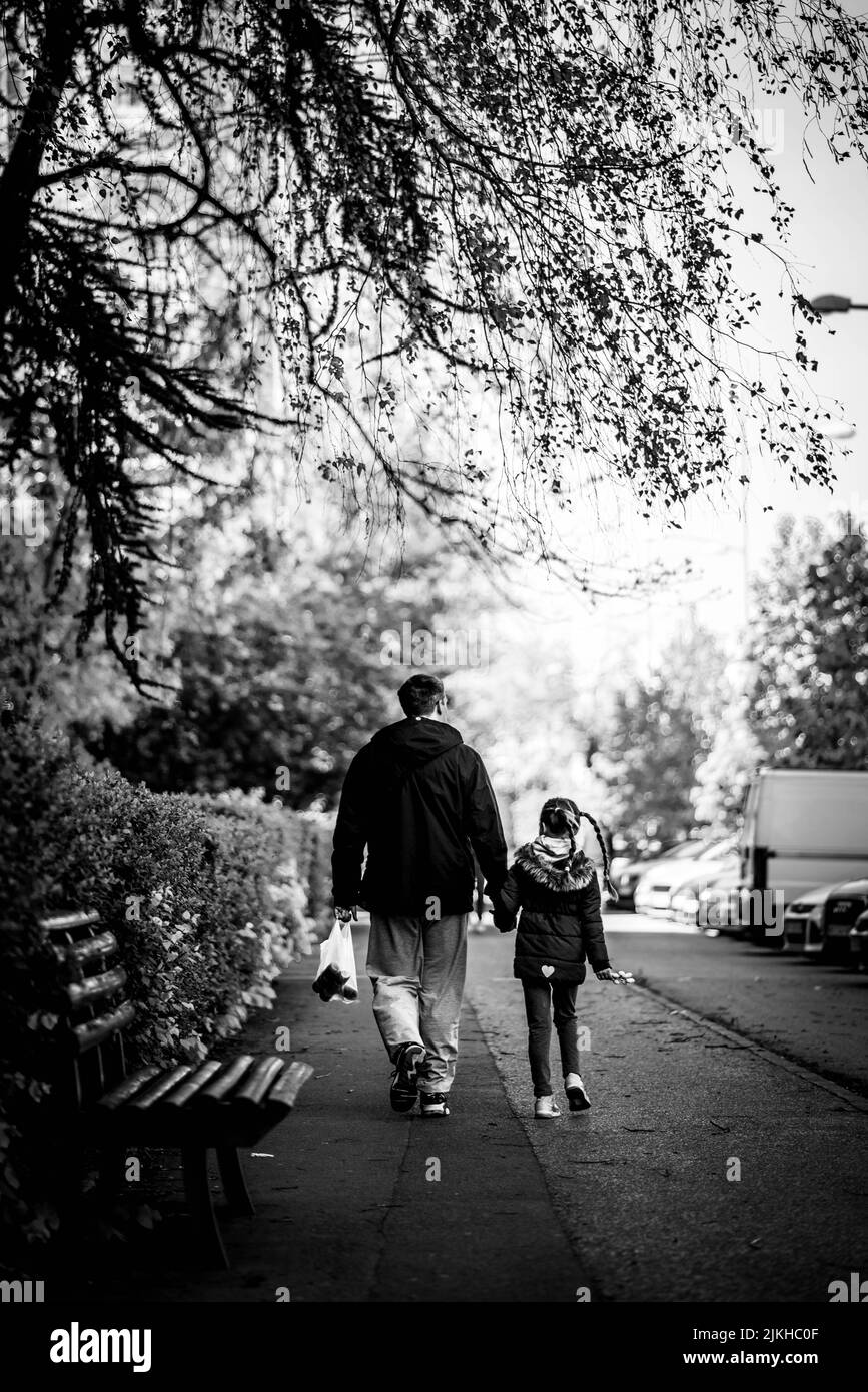 A vertical shot of a young man with his girl walking in the garden ...