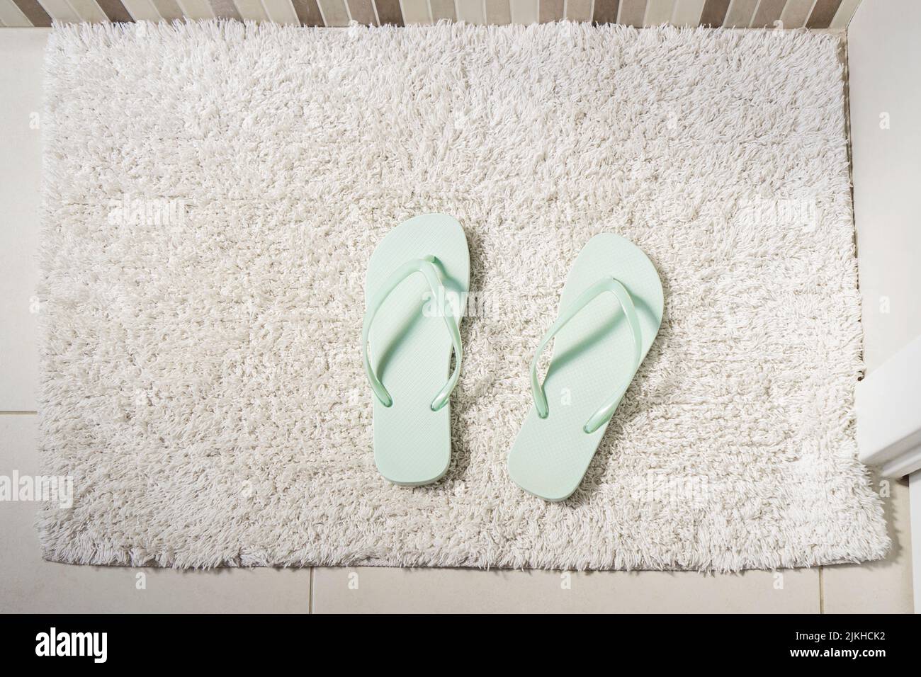 Pair peppermint-coloured flip-flops on white carpet in bathroom ...