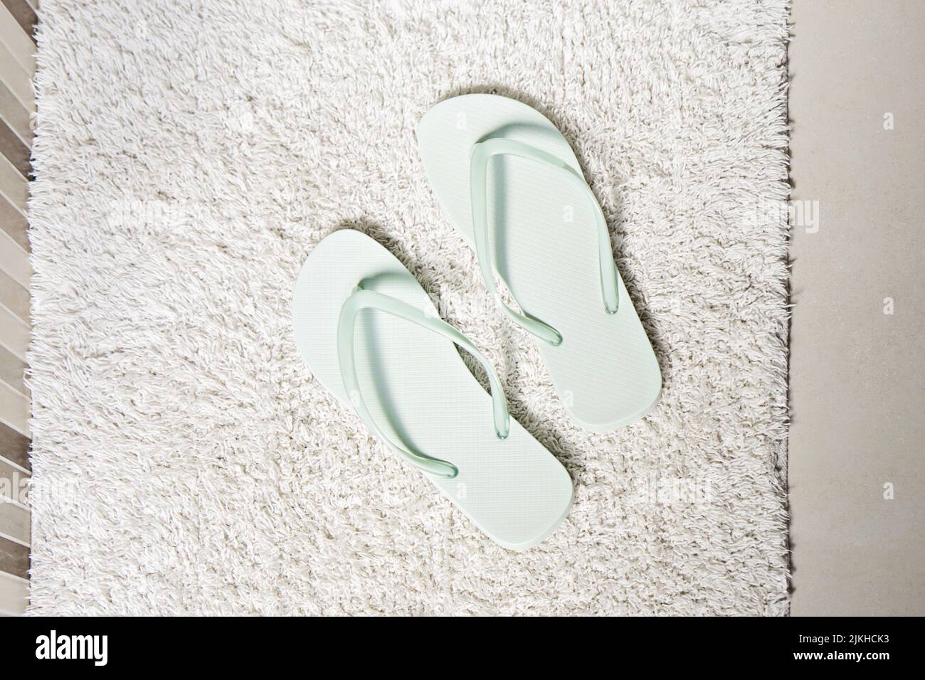 Pair peppermint-coloured flip-flops on white carpet in bathroom ...