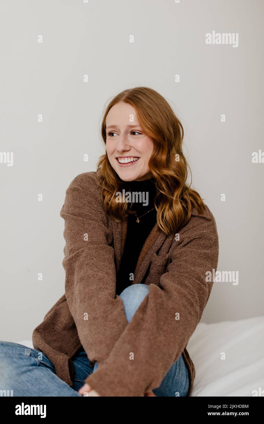 A beautiful Caucasian female posing for a photo in a studio on a white ...
