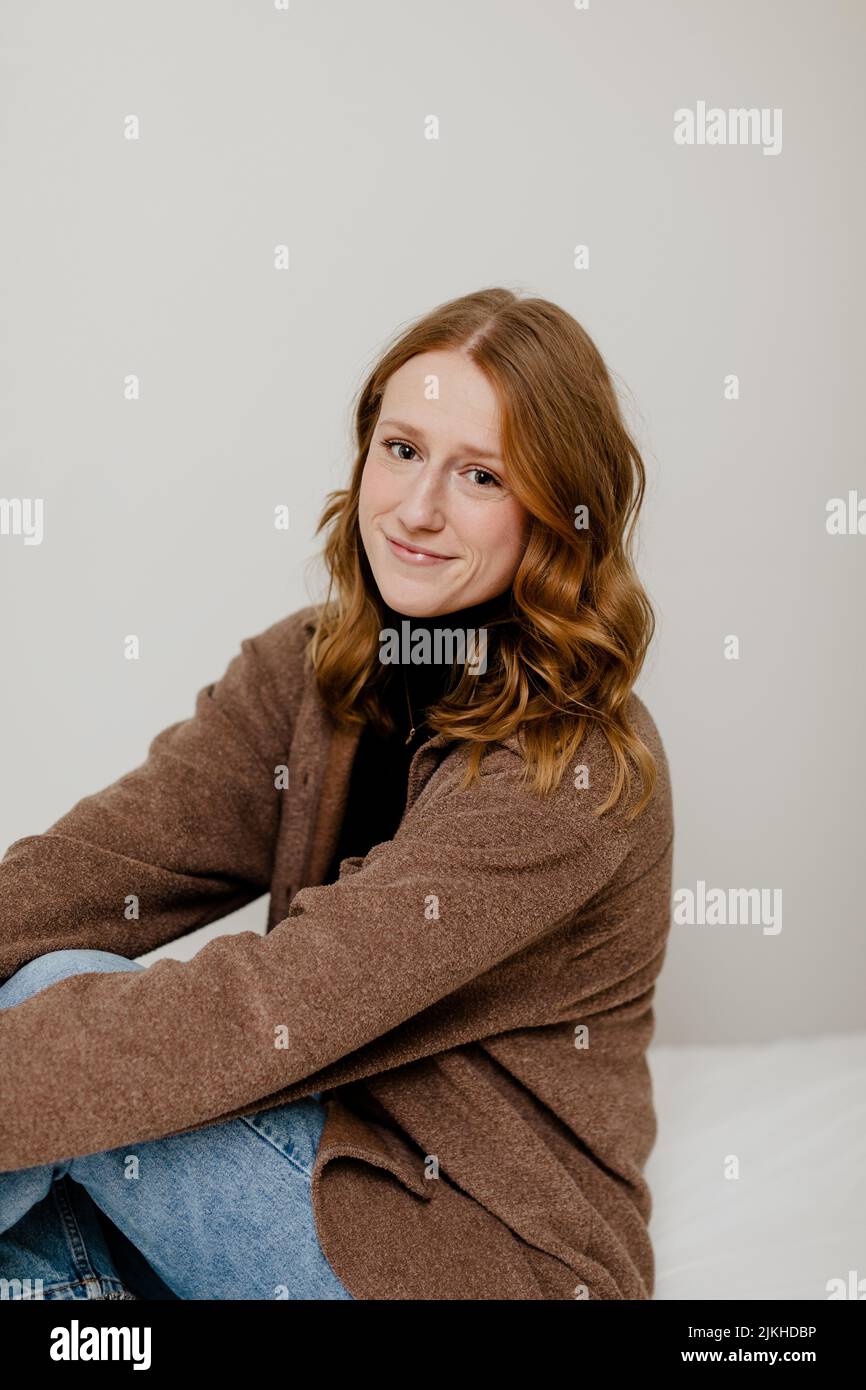 A beautiful Caucasian female posing for a photo in a studio on a white ...