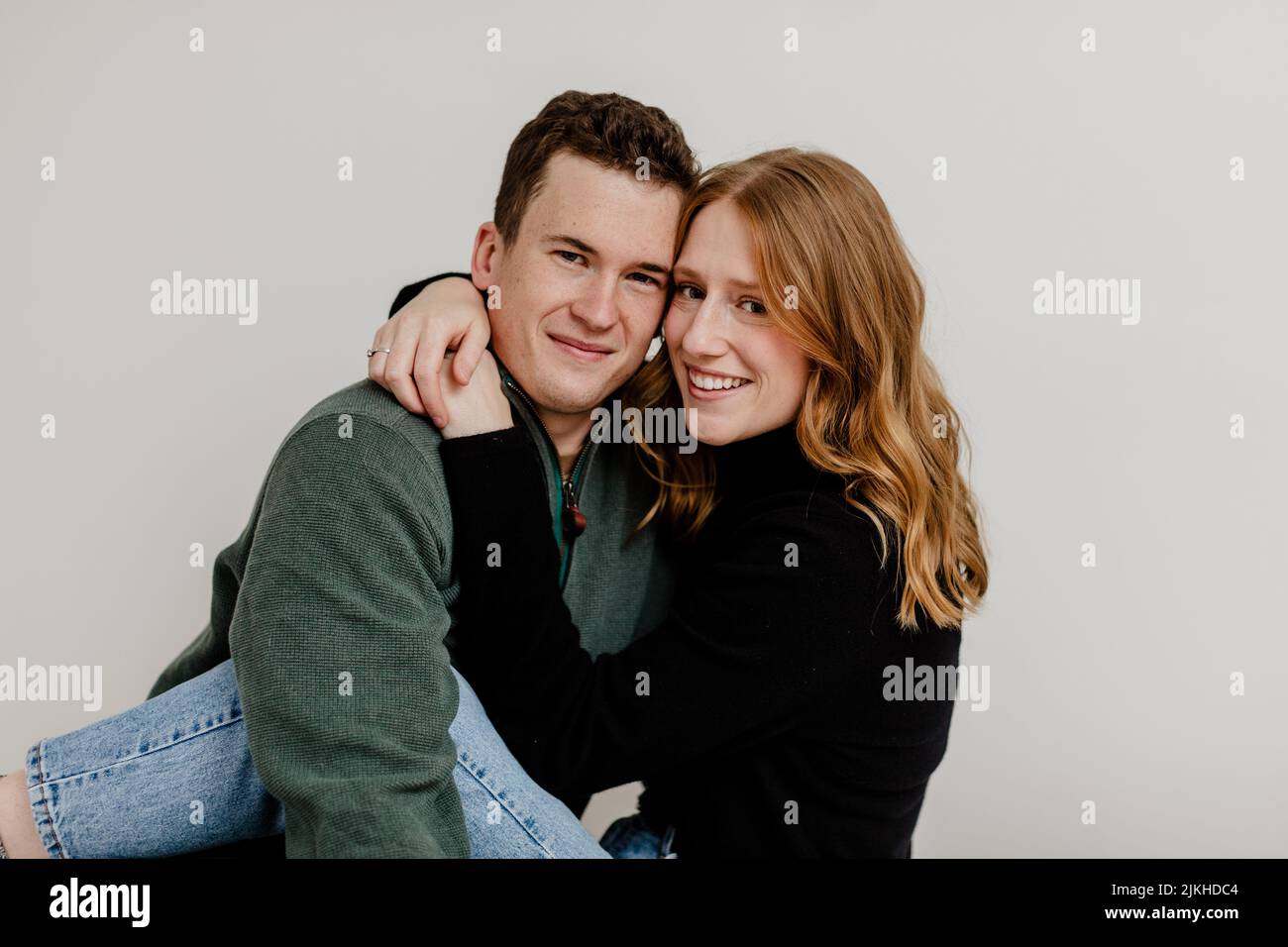 A beautiful Caucasian couple posing for a photo in a studio on a white ...