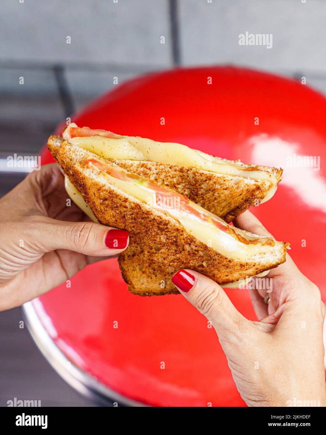 A vertical closeup of female hands holding cheese and ham sandwich ...