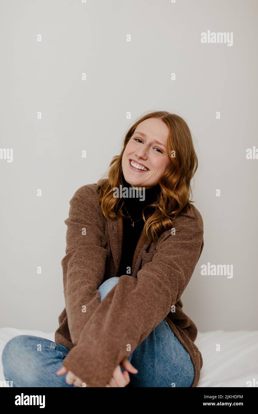 A beautiful Caucasian female posing for a photo in a studio on a white ...