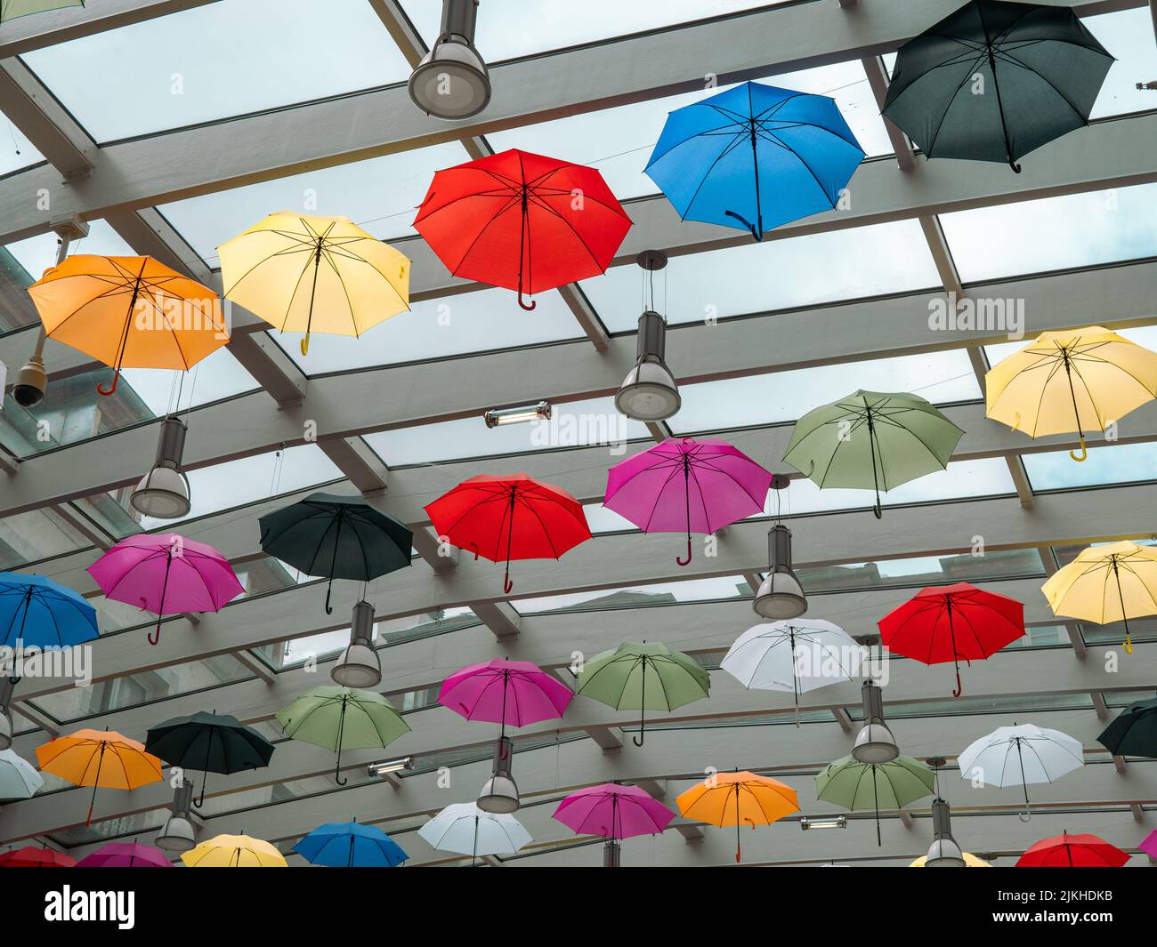 A low angle shot of colorful umbrellas hanging on a glass ceiling of a ...