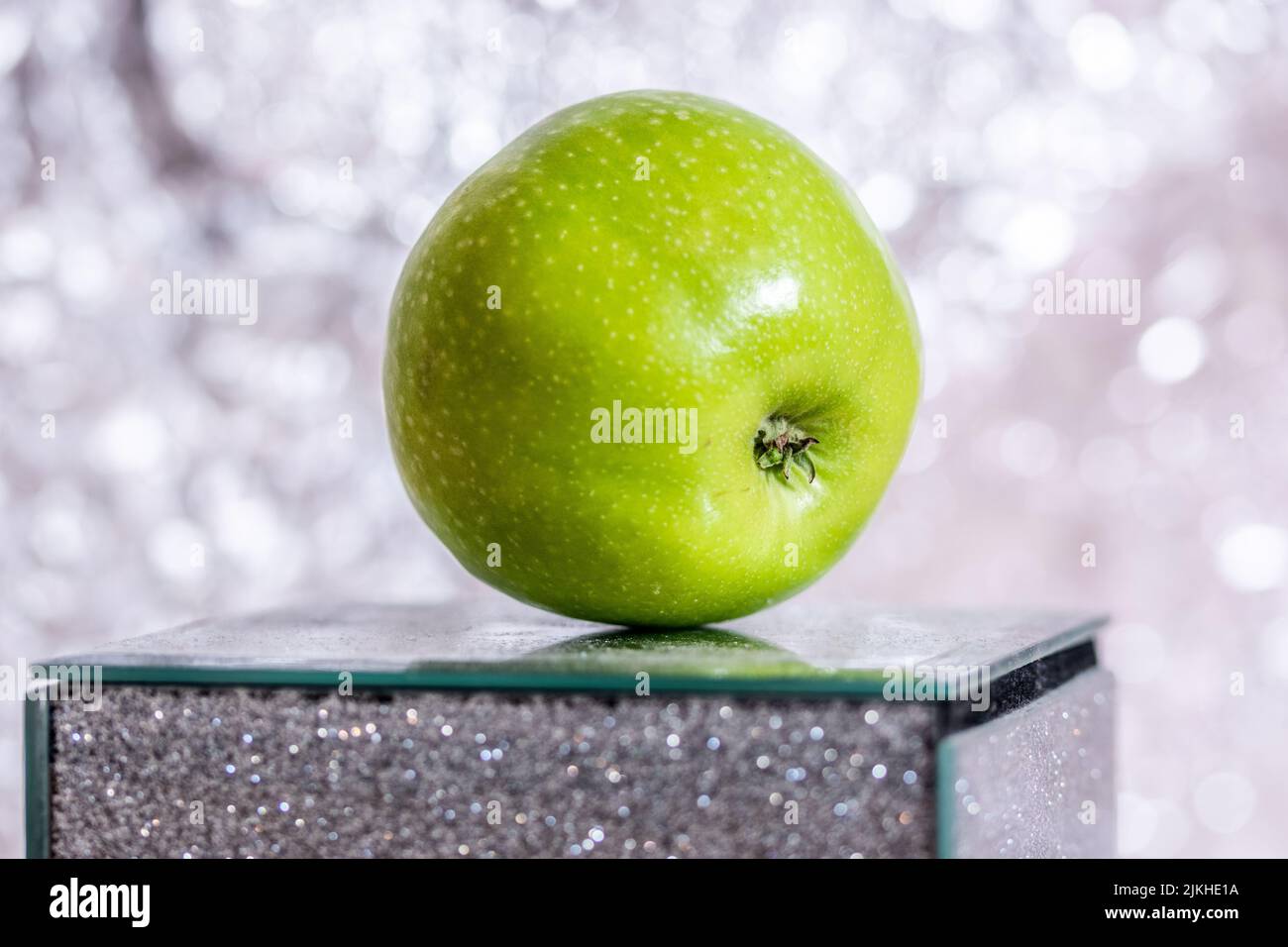 A closeup of ripe round green apple on shiny glass surface Stock Photo ...
