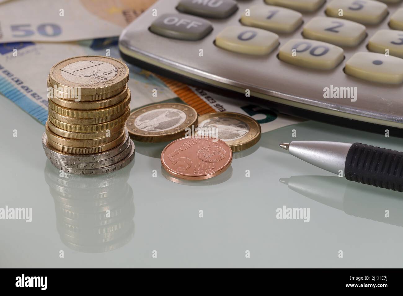 A stack of Euro coins and a calculator with burred Euro banknotes Stock ...