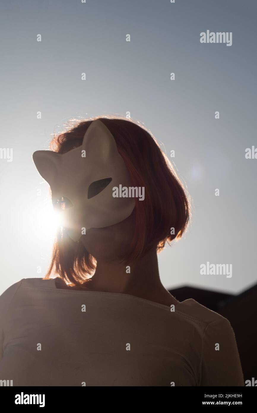 A beautiful redhead and mysterious woman with a white cat face mask ...