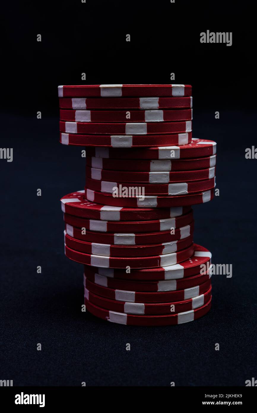 A vertical shot of a stack of colorful poker chips in a dark background ...