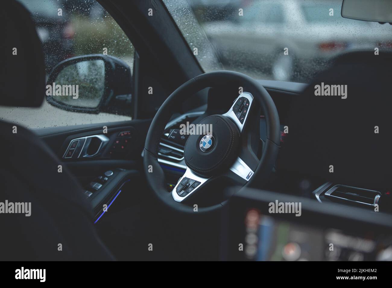 The interior of a luxury BMW X7 car with wet raindrop covered windows ...