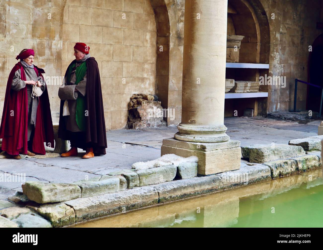 The two people dressed in medieval costumes are talking by the pool in ...