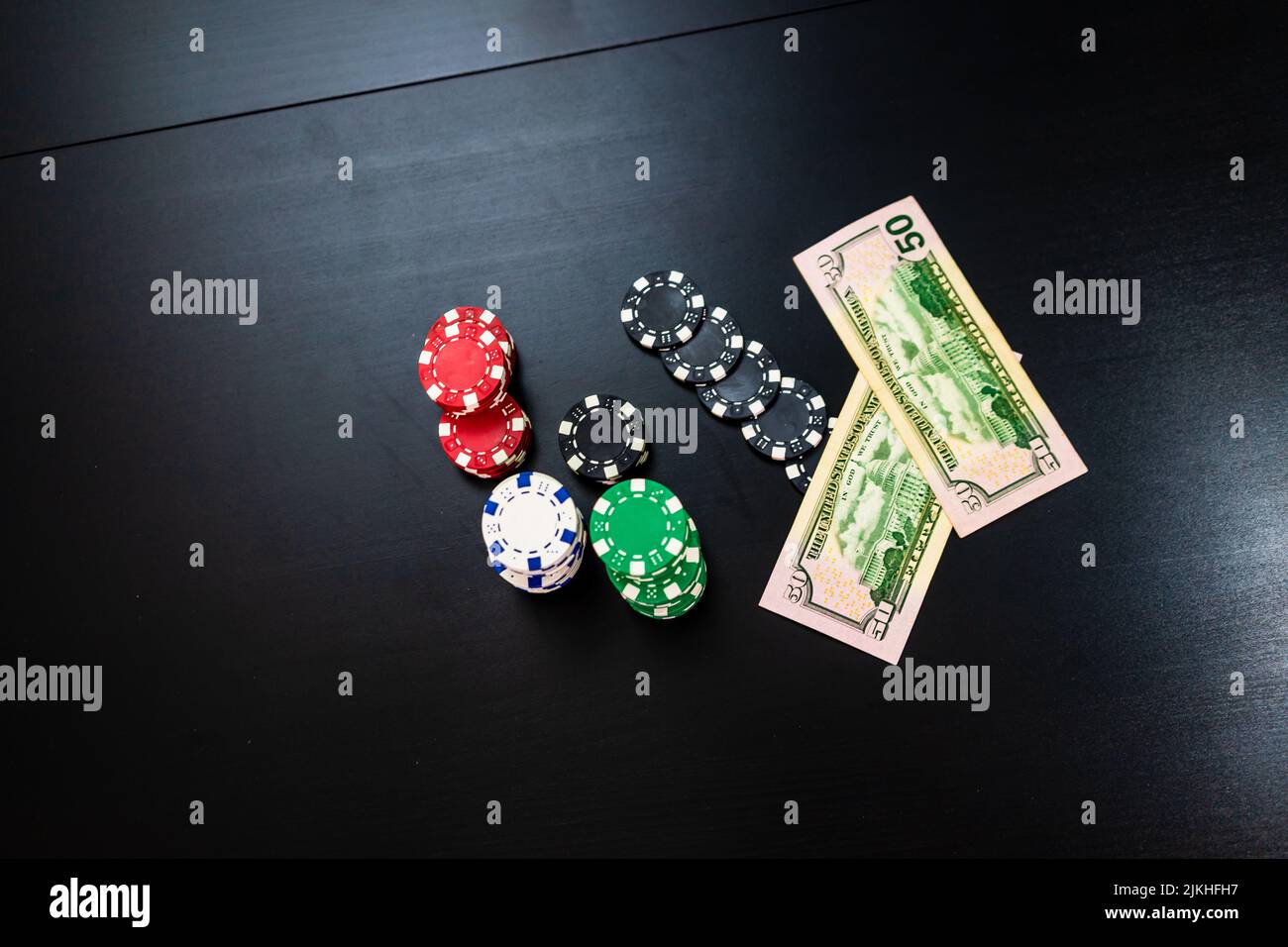 A top view of stacks of poker chips with money on a black table Stock ...