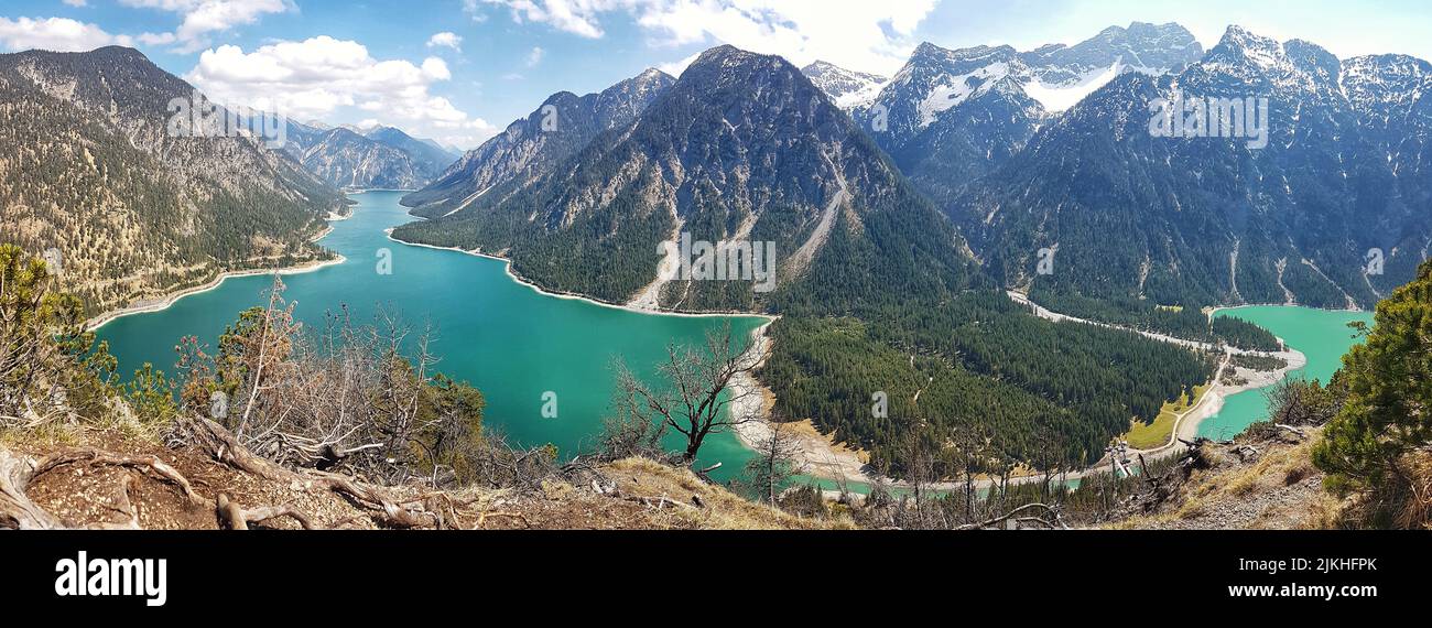 A panoramic view of the blue Plansee lake surrounded by mountains in ...