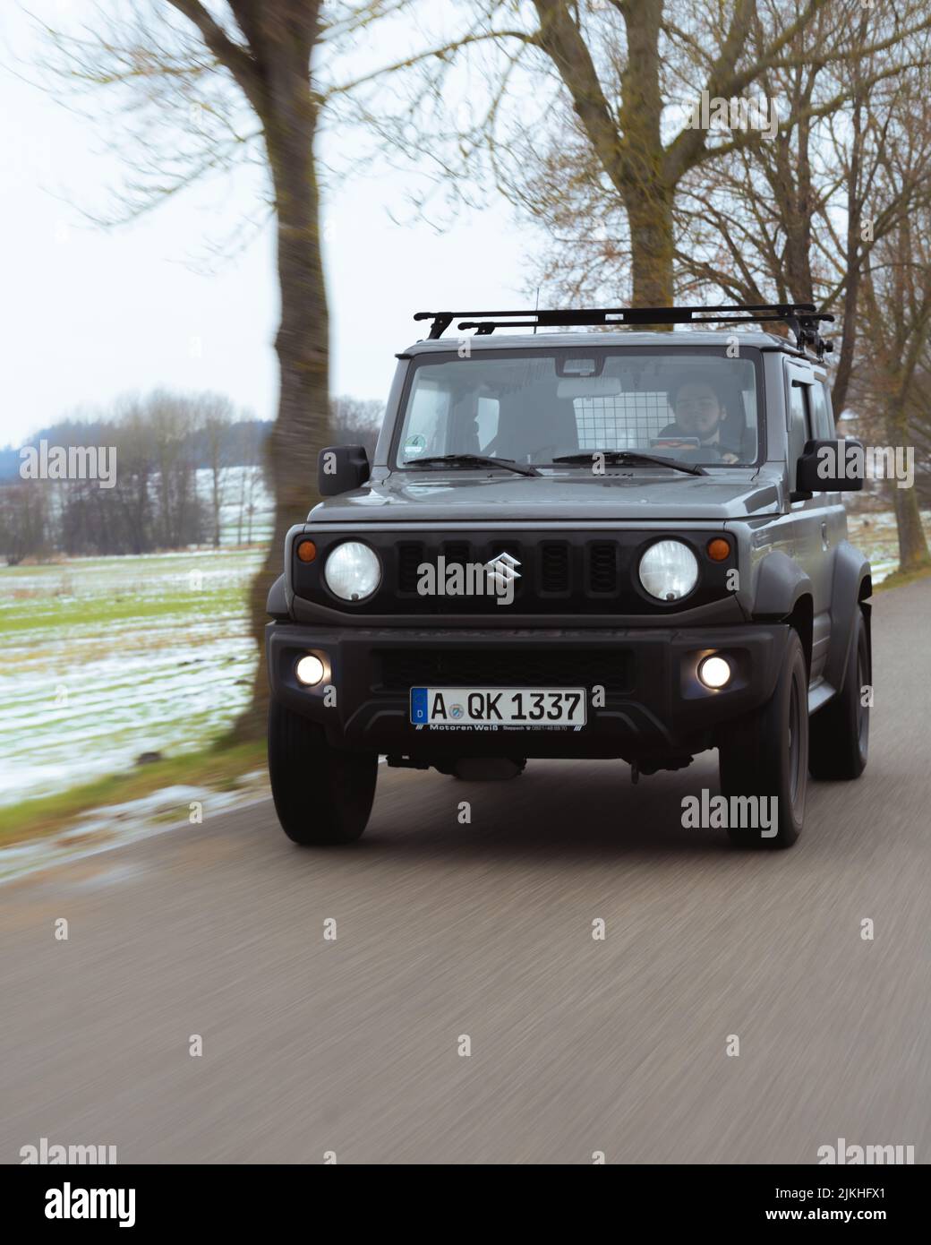 A vertical shot of black Suzuki Jimny driving on a country road Stock ...