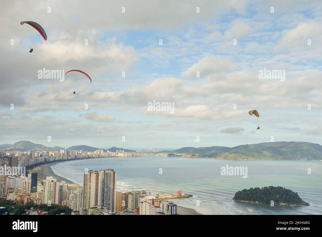 paragliders flying on cloudy sky above Santos city beach in Brazil ...