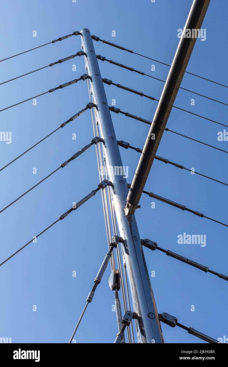 A vertical low angle shot of cables on a pedestrian bridge against the ...