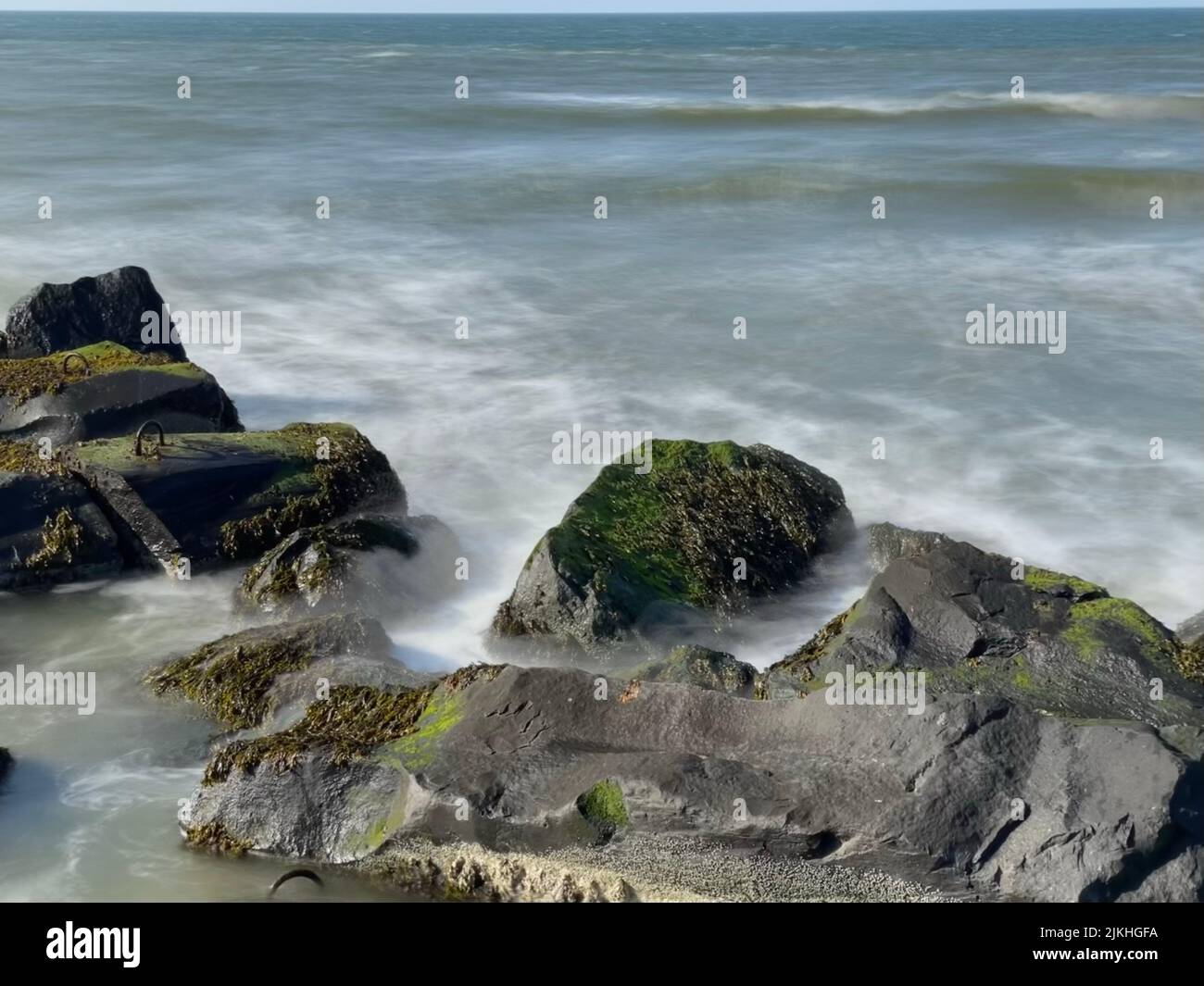 The long exposure of sea wave foam touching rocks at beach Stock Photo ...