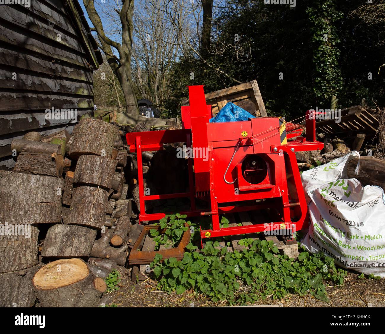 A red log splitter next to a woodpile Stock Photo - Alamy