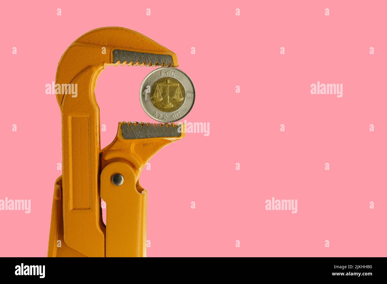 Ethiopian one Birr coin held in an orange plumber wrench on a pink ...