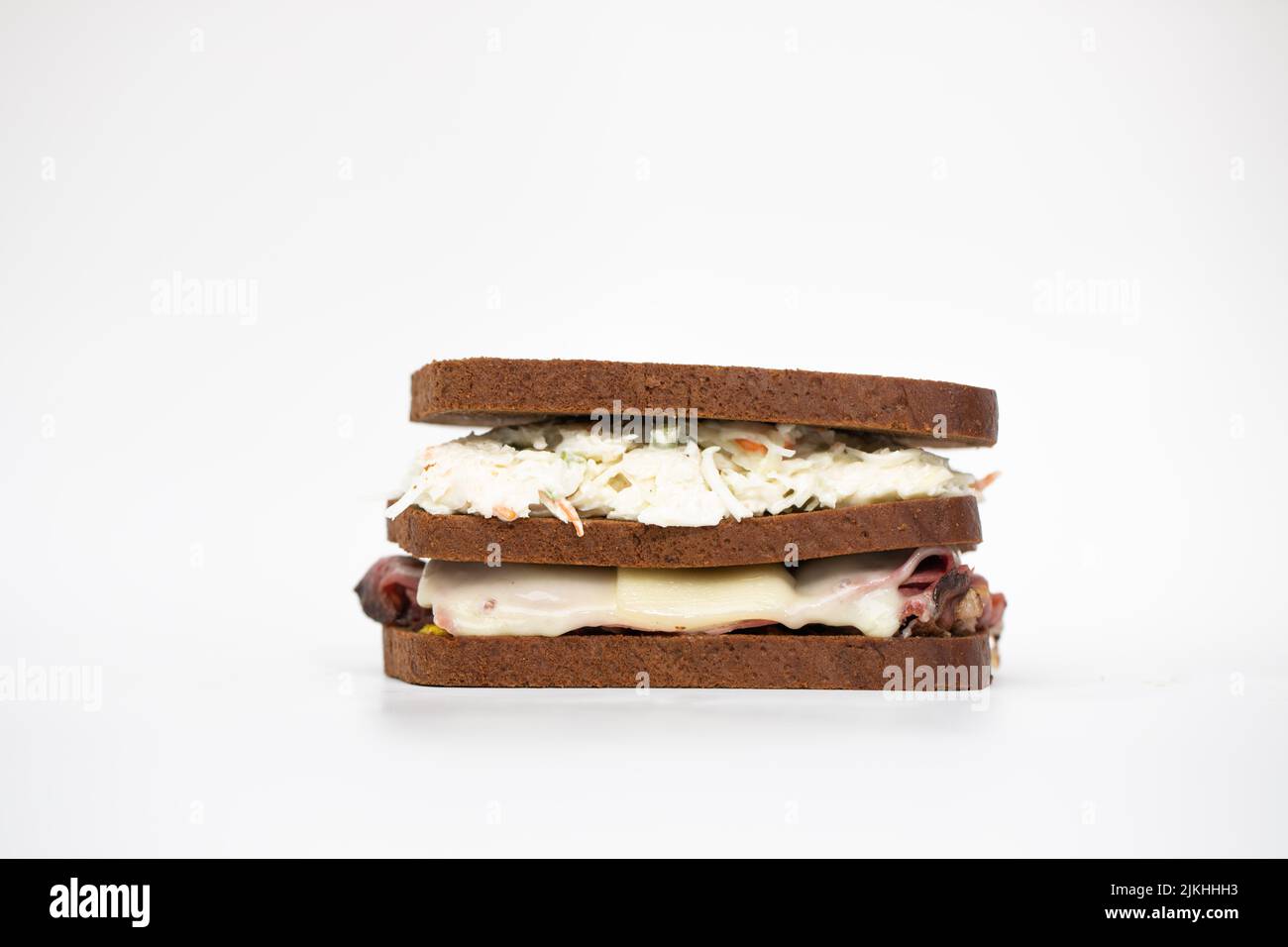 A view of a three-layer sandwich with vegetables, becon and cheese on ...