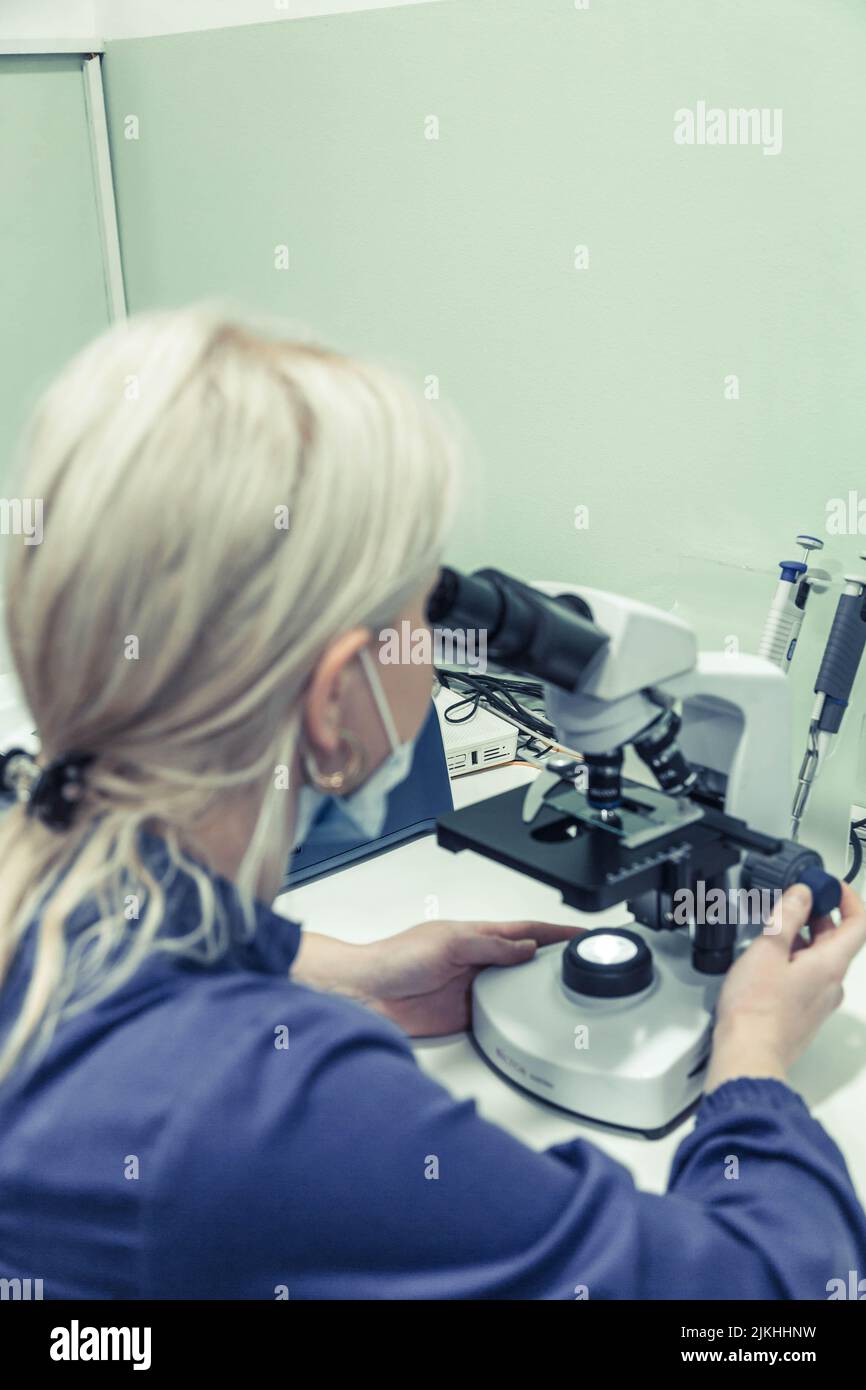 A shot of a female scientist looking through a binocular biological ...