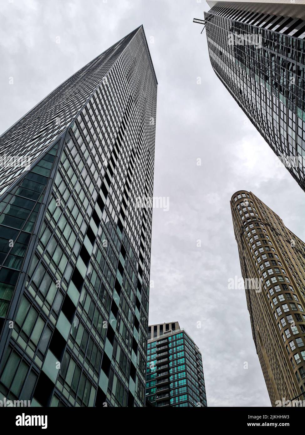 A vertical low angle view of tall office towers against the cloudy sky ...