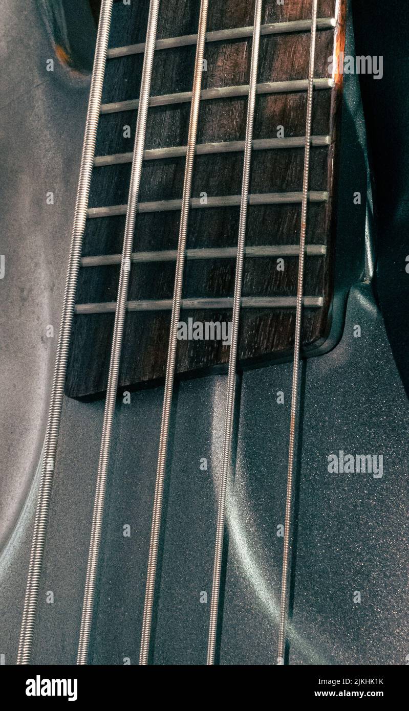 A vertical closeup of a gray bass guitar with five strings Stock Photo ...