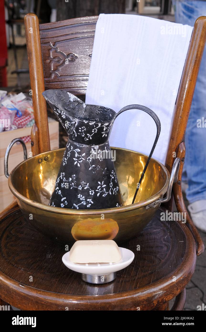 A vertical shot of an old iron pitcher in a bronze bowl next to a bar ...