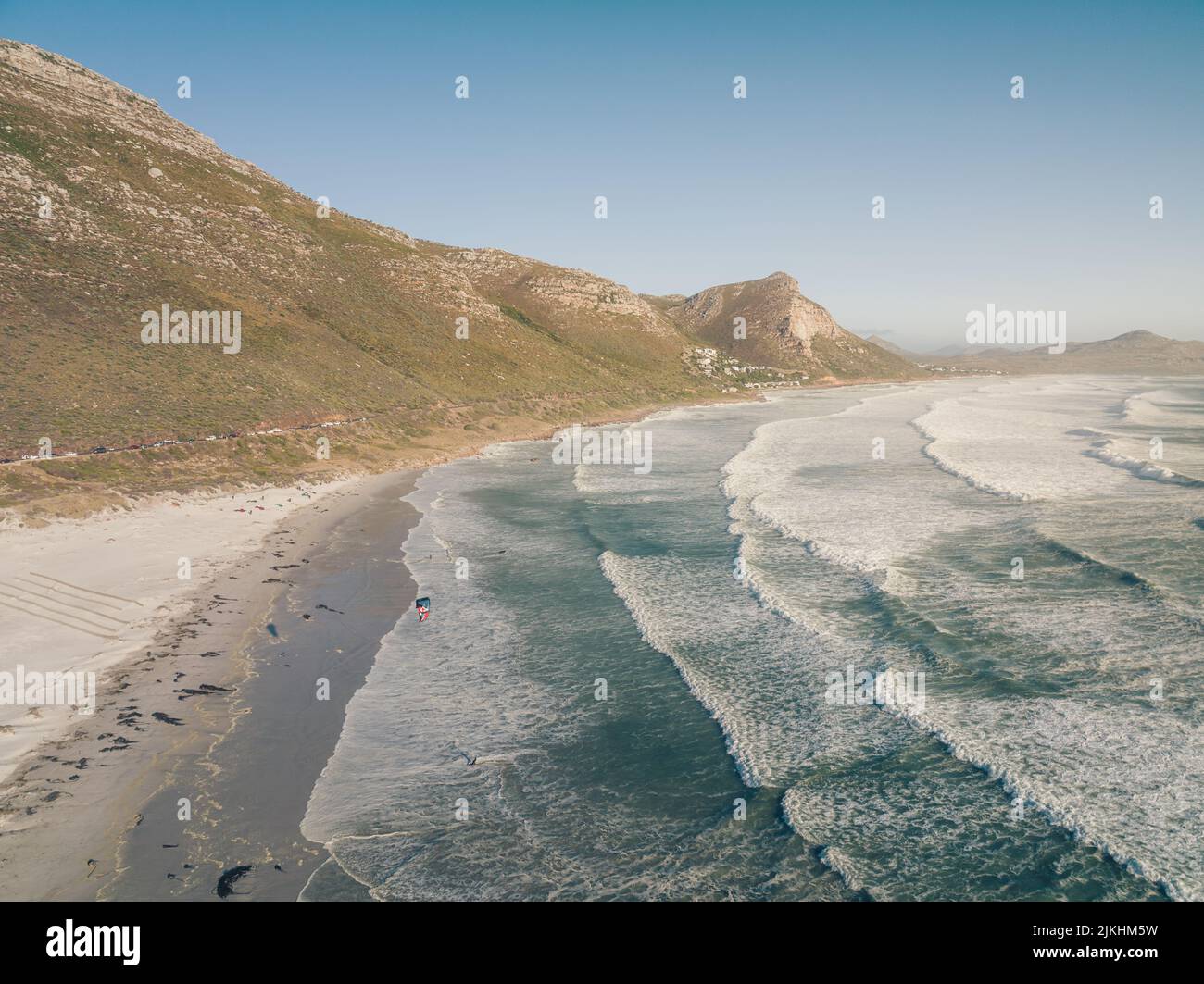 A high angle shot of a beach with blue ocean waves with mountains and ...