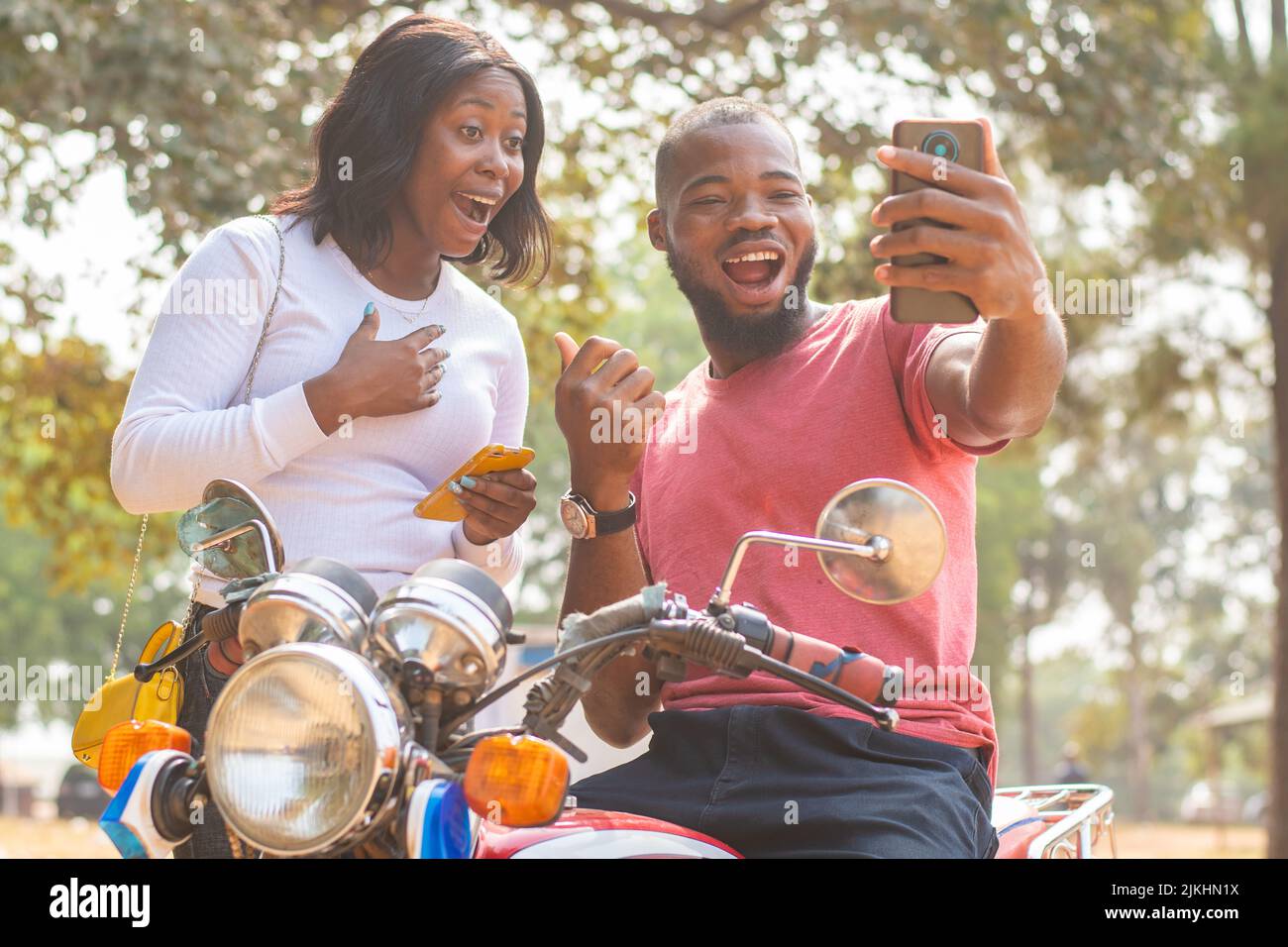 african man and woman look at phone excitedly Stock Photo - Alamy