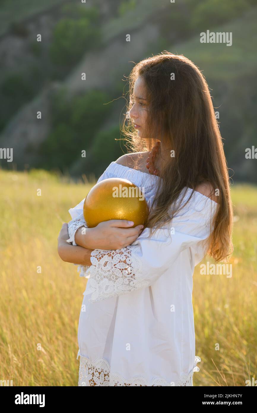 Teenage girl with a gymnastic ball on the background of a ravine ...