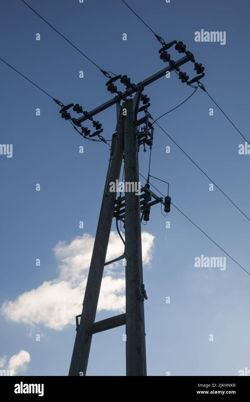 A low angle closeup of an electric power cable tower on a blue sky ...
